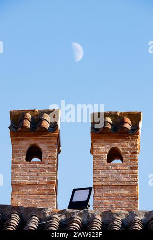 Two chimneys with the moon in San Carlos del valle Stock Photo - Alamy