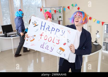 Business colleagues with poster celebrating April Fools' Day at office ...