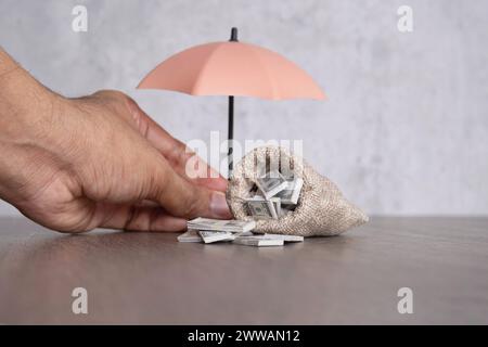 Hand holding umbrella protecting bag of money. Financial safety, income ...