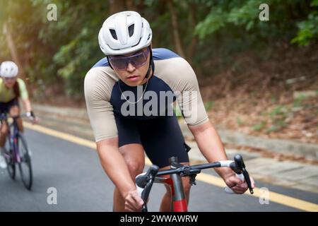 Asian male biker riding road bike, front view isolated on white ...