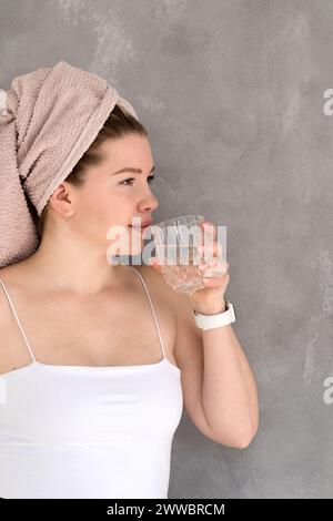 Woman drinking water during skincare routine. Morning self-care routine ...