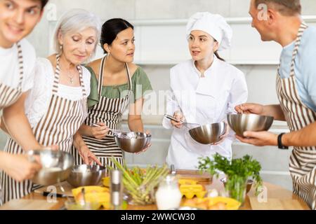 Young female cook teaches to cook group of people Stock Photo - Alamy