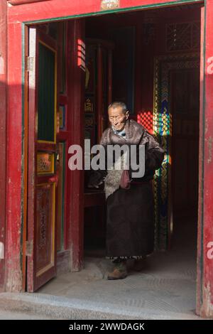 Elderly male pilgrim, face caught in sunlight, leaving a room with a ...