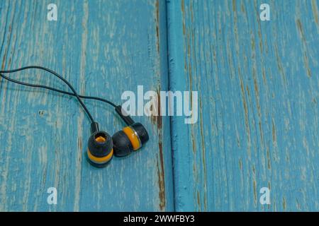 Set of black and yellow used ear buds on blue wood grain background ...