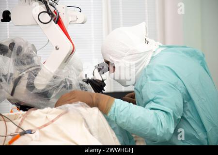 A neurosurgeon doctor looks into a microscope during an operation ...
