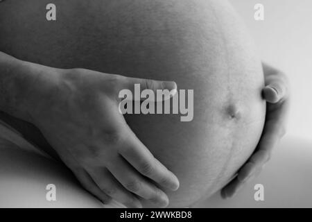 Description: Closeup of woman sitting and gently holding her very round ...