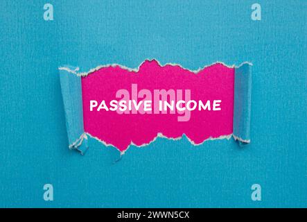 Passive income words written on torn paper piece with wooden background ...