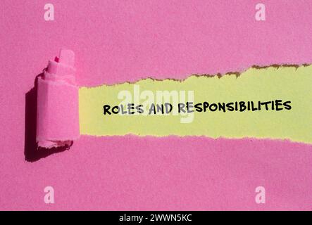Roles and responsibilities words written on torn paper piece with blue ...
