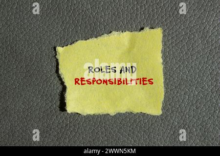 Roles and responsibilities words written on torn paper piece with blue ...