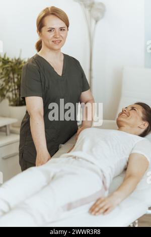 Healthcare time. smiling female massage therapist in massage cabinet with client doing checkup ...