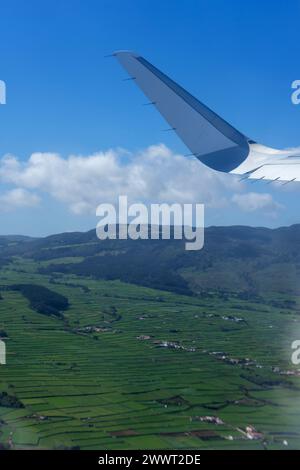 Wing of airplane soaring over fields on Terceira Island, Azores. Aerial ...