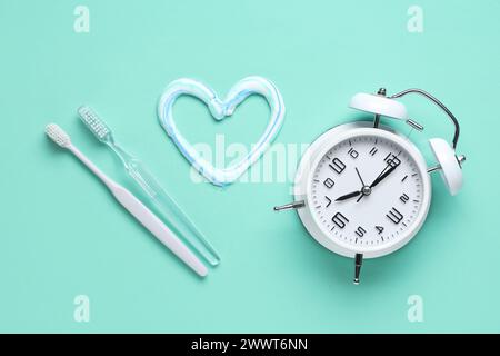 Heart made of toothpaste, clock, dental floss and toothbrush on lilac ...