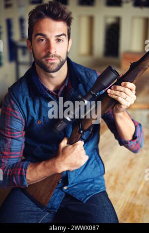 Portrait of hunter or ranger with gun or rifle in the forest looking ...