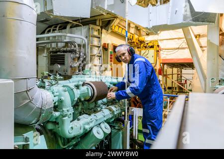 Marine Engineer in blue overall working in Engine room of ship. Work at ...