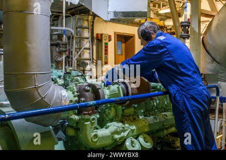 Marine Engineer in blue overall working in Engine room of ship. Work at ...