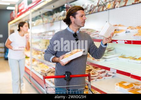 Attentive customer chooses chicken meat in the meat department of ...