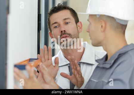 two man wall holding spirit level Stock Photo - Alamy