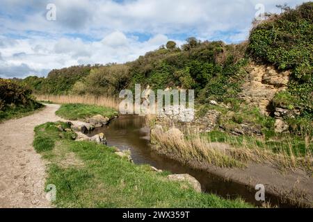 A rough sandy footpath next to the Par Polmear River flowing towards ...