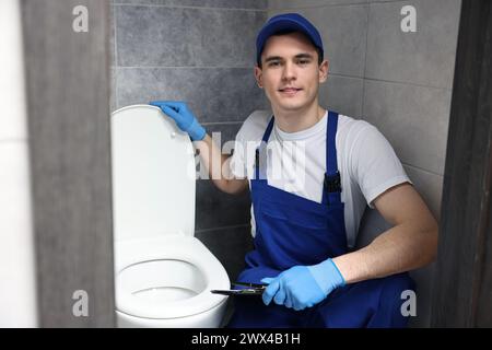 Plumber examining toilet bowl in water closet Stock Photo - Alamy