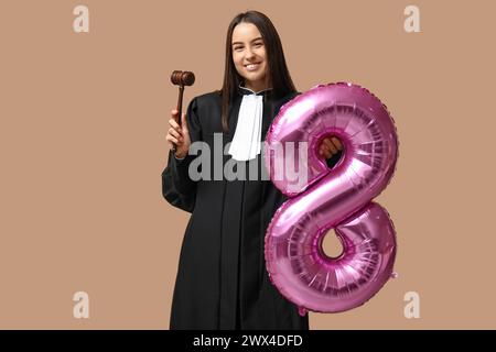 Young female judge with balloon in shape of figure 8 on beige ...