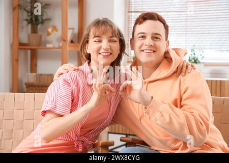 Young deaf mute couple in armchairs using sign language at home Stock ...