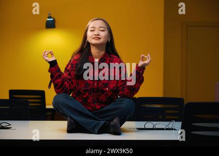 Calm female employee practicing yoga at workplace Stock Photo - Alamy