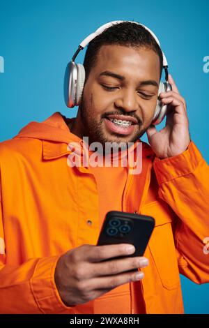An attractive happy African man scrolling his phone isolated on a brown ...