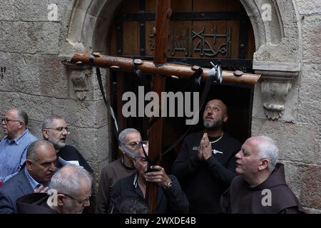 Christian Arab worshipers stand with a large wooden cross next to a ...