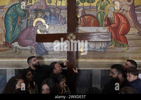 Christian Arab worshipers stand with a large wooden cross next to a ...