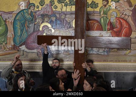 Christian Arab worshipers stand with a large wooden cross next to a ...