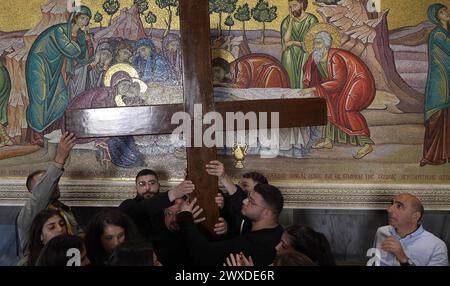 Christian Arab worshipers stand with a large wooden cross next to a ...