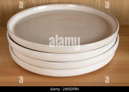 A stack of beige ceramic plates in a wooden cupboard Stock Photo - Alamy