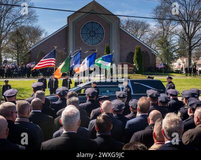 A hearse car drives as police officers inspect the area where a fire ...