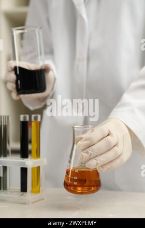 Woman holding beaker and flask with different types of crude oil on ...