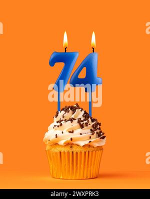 Number 74 blue celebration candle on white wooden background with ...