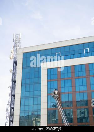 Cleaning windows in a large glass building. Work at height on a lift ...
