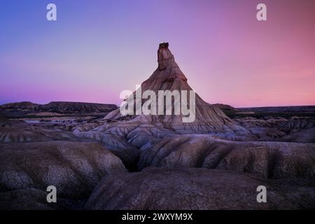 The iconic outline of a badlands rock formation is silhouetted against ...