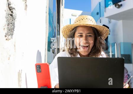 Digital nomad, woman in the hat, a business woman with a laptop sits on ...