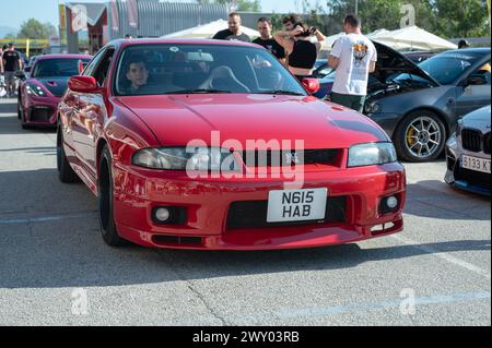 Front view of a red ninth-generation Nissan Skyline GT-R33 at a ...