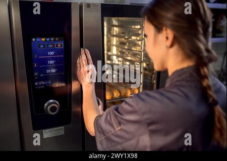 Woman baker using electrical oven for baking French baguettes Stock ...