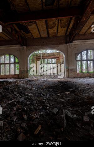Interior view of a dilapidated building with arched windows and debris ...
