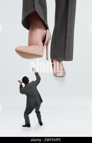 Big woman stepping onto small man on white background Stock Photo - Alamy