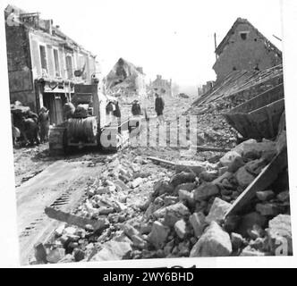 An armoured bulldozer clears a road through the remains of a town on ...