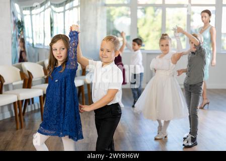 Enthusiastic preteen children dancing waltz in pairs in dance school ...