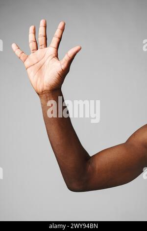 A mans arm is raised high in the air, hand held up with fingers spread ...