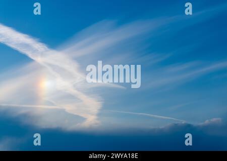 Sky with cirrus, stratus clouds, airplane trail and halo from the sun ...