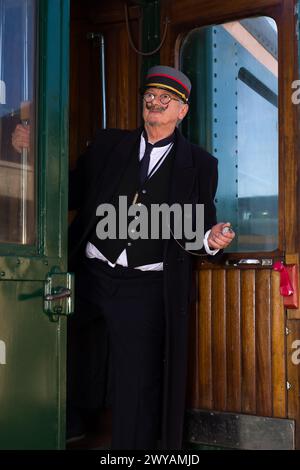 Reenactment scene of a vintage railway conductor at the departure of ...