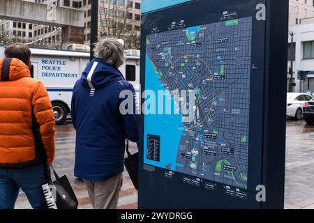 Seattle, USA. 10th Mar, 2024. People passing a tourist map and mobile ...
