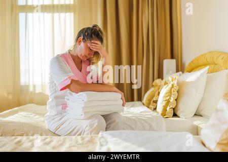 Image of sad overworked hotel maid sitting on the bed in a room Stock ...