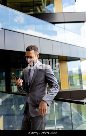 Suited man with arms crossed stands proudly before a sleek building ...